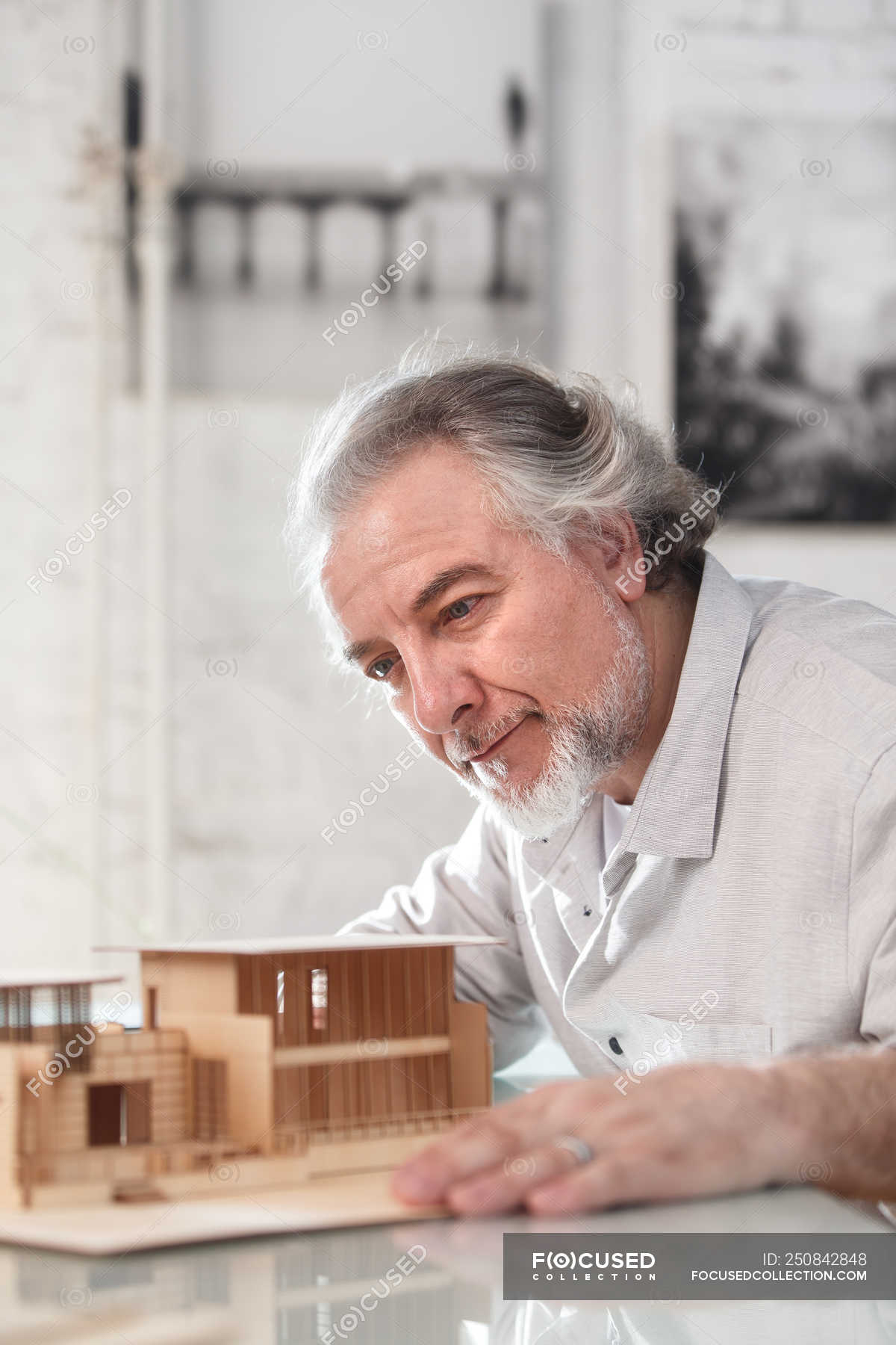 Professional smiling mature architect working with building model at ...