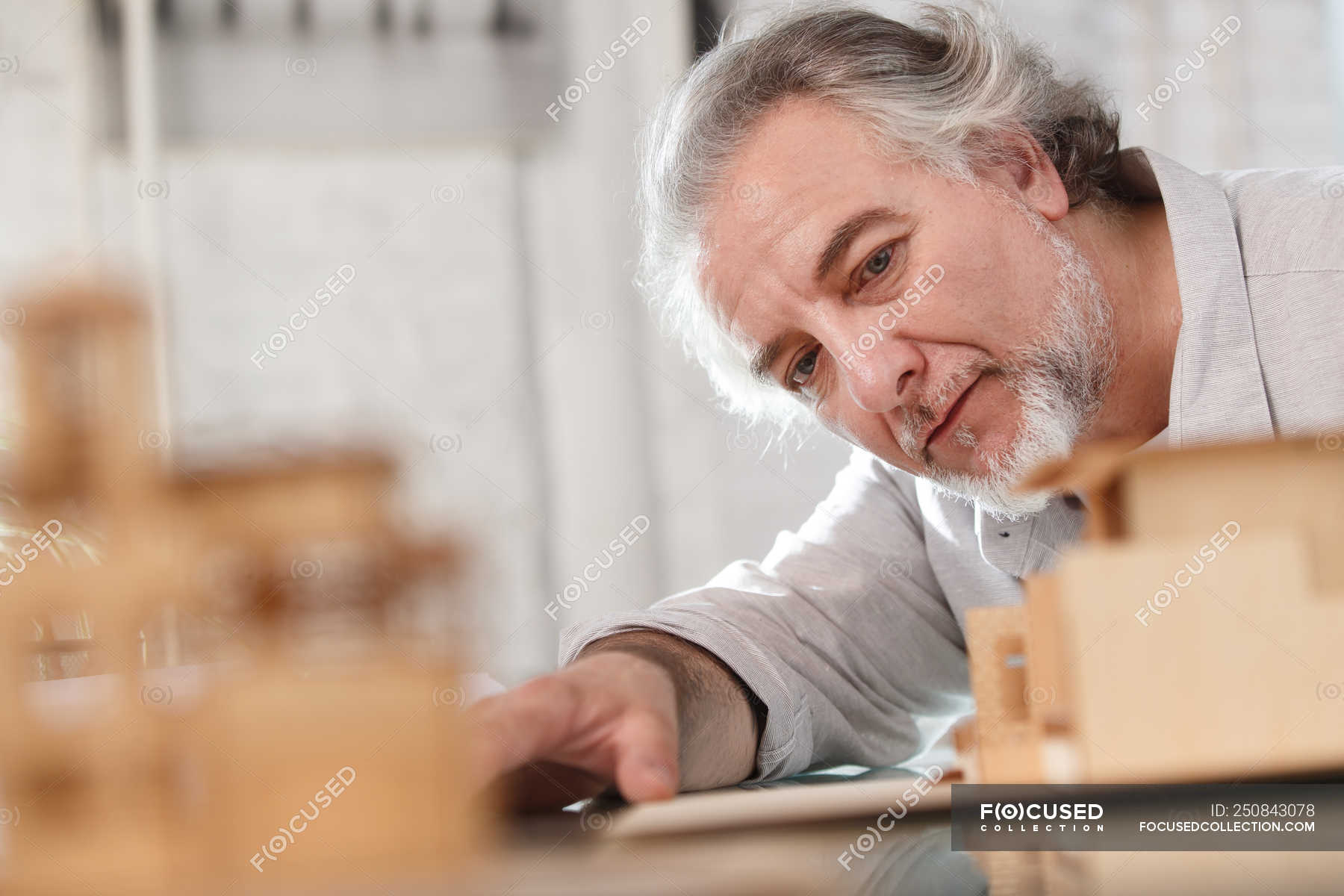 Professional mature architect working with building model at workplace ...
