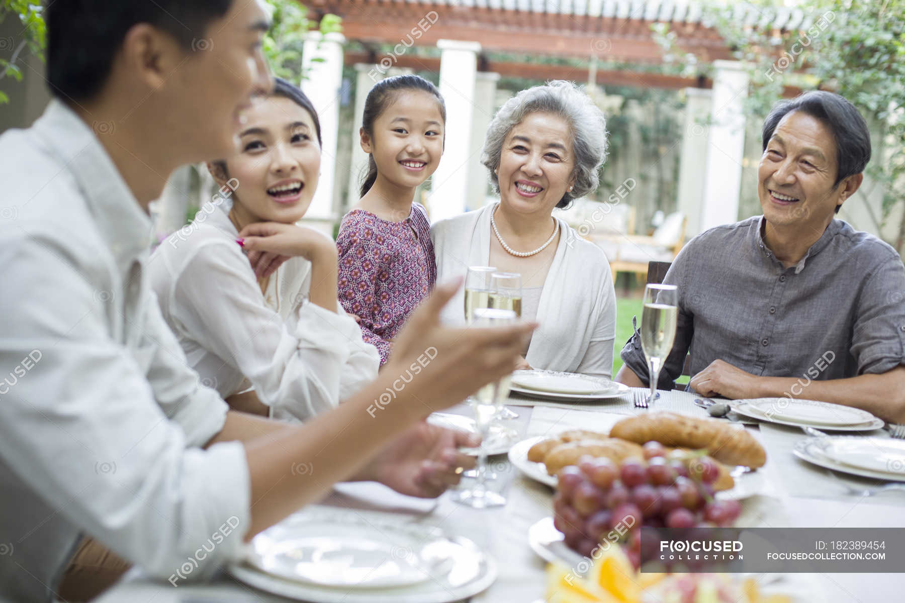 Chinese family talking at dining table in courtyard — girl ...