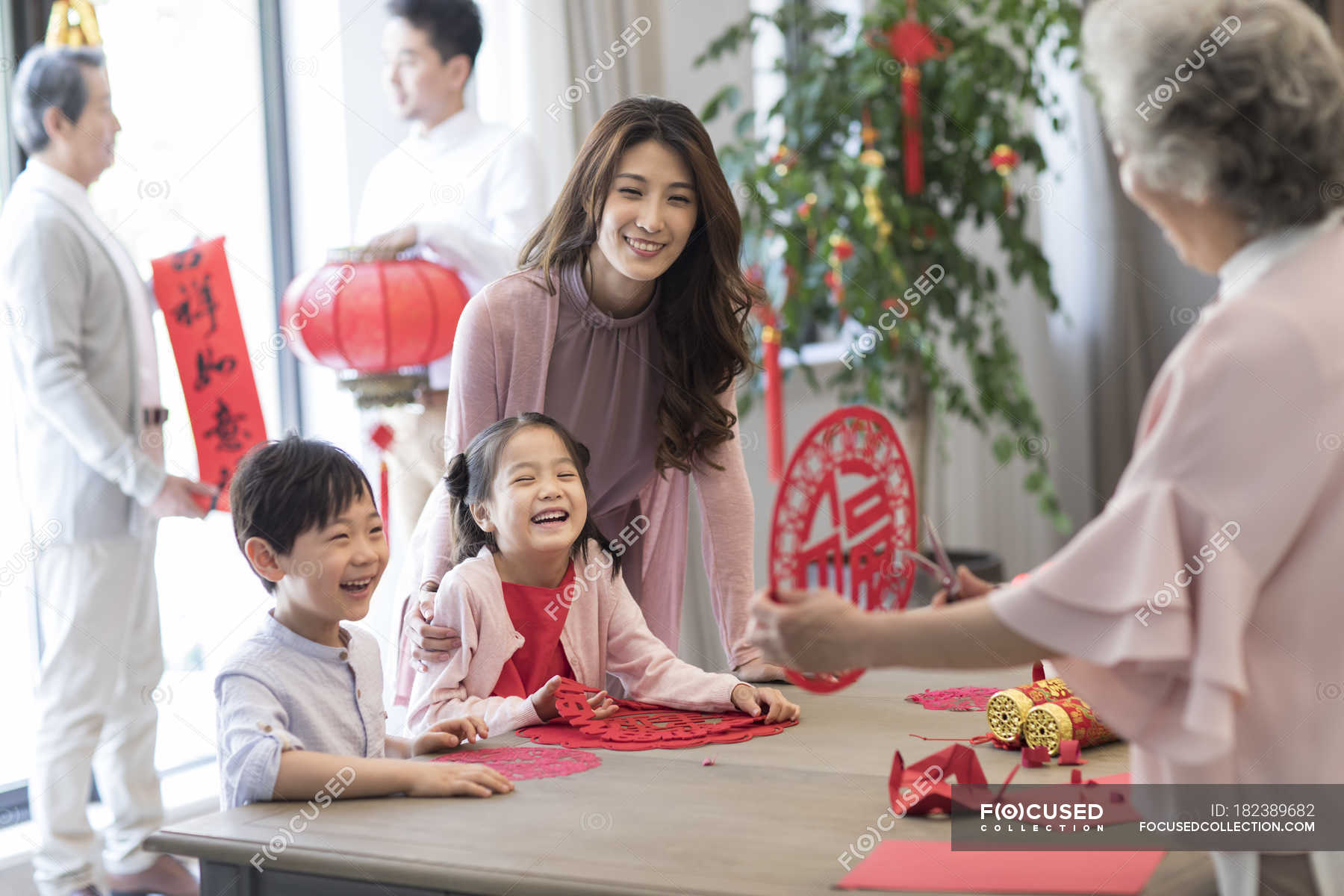 Grandmother with children and mother making Chinese New Year paper-cut ...