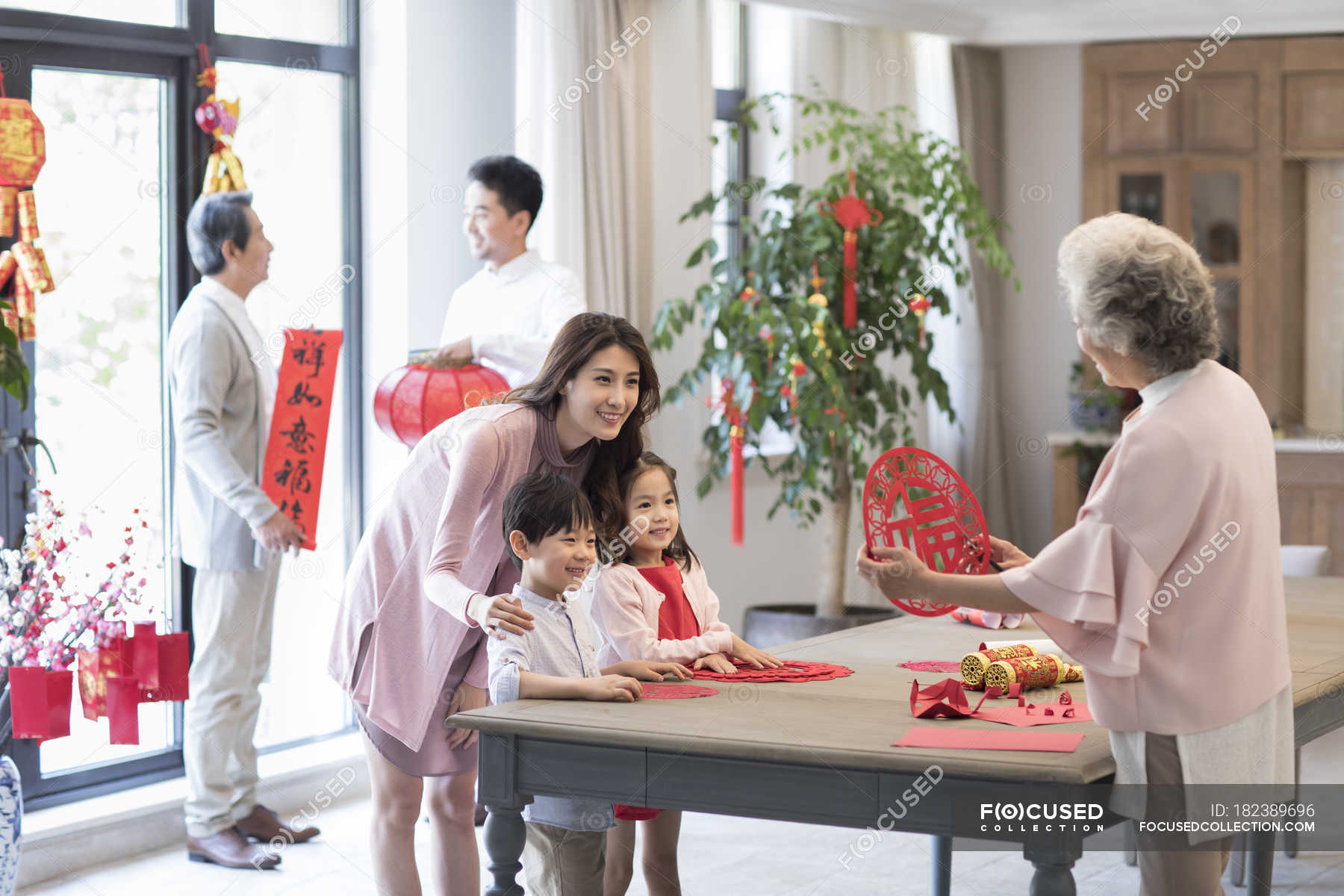 Grandmother with children and mother making Chinese New Year paper-cut ...