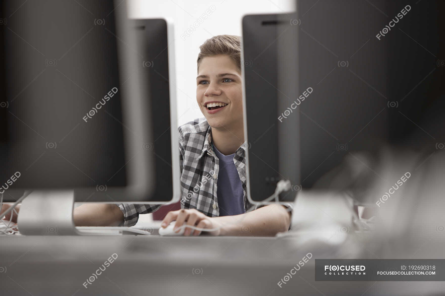 Pre-adolescent boy working in computer laboratory with rows of computer ...