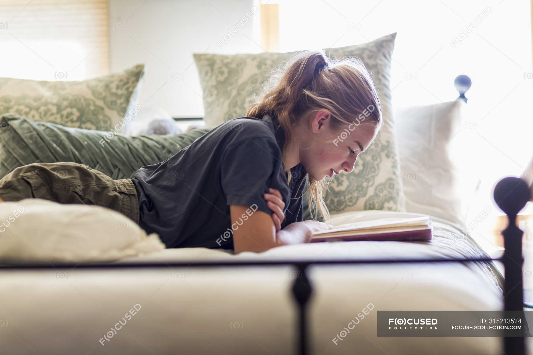 Teenage Girl Lying In Bed And Reading By Window Light Study Female 