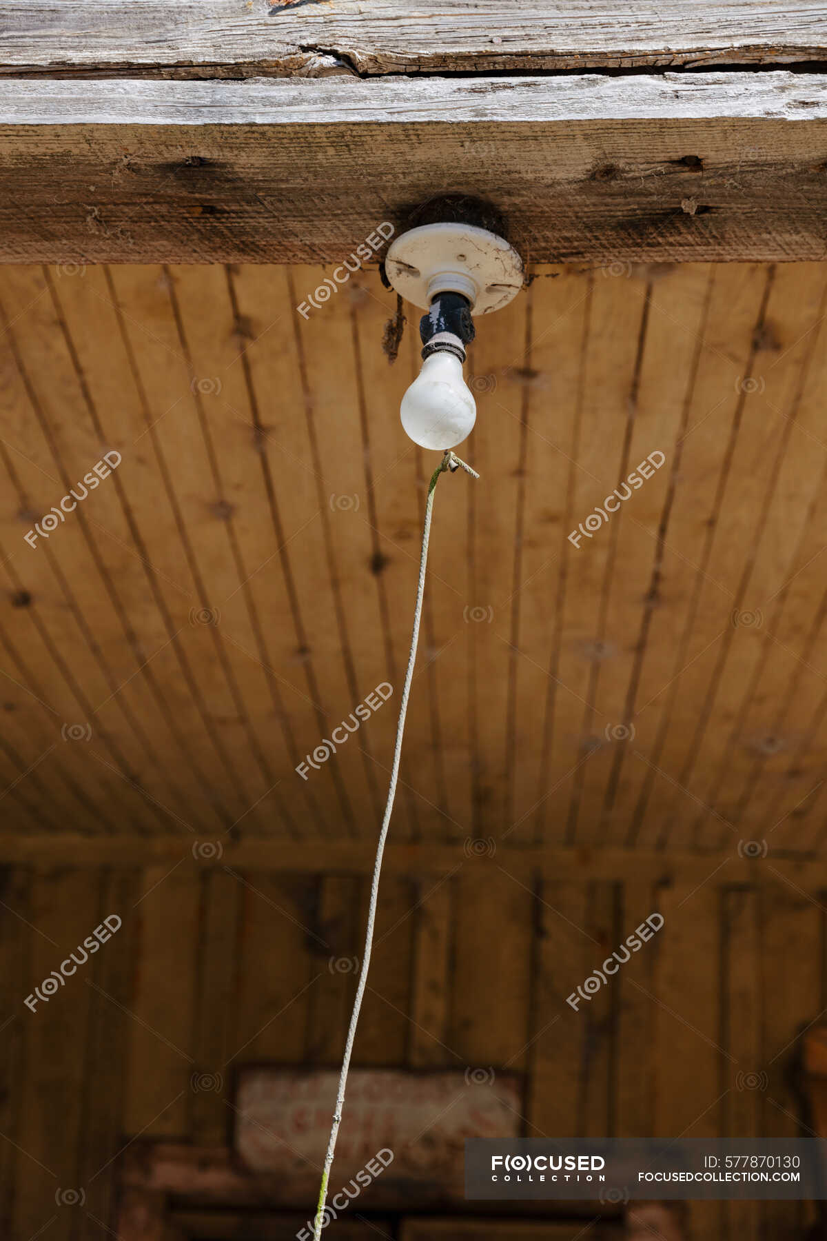 Old incandescent light bulb on a porch beam with a string pull control ... Old incandescent light bulb on a porch beam with a string pull control ...