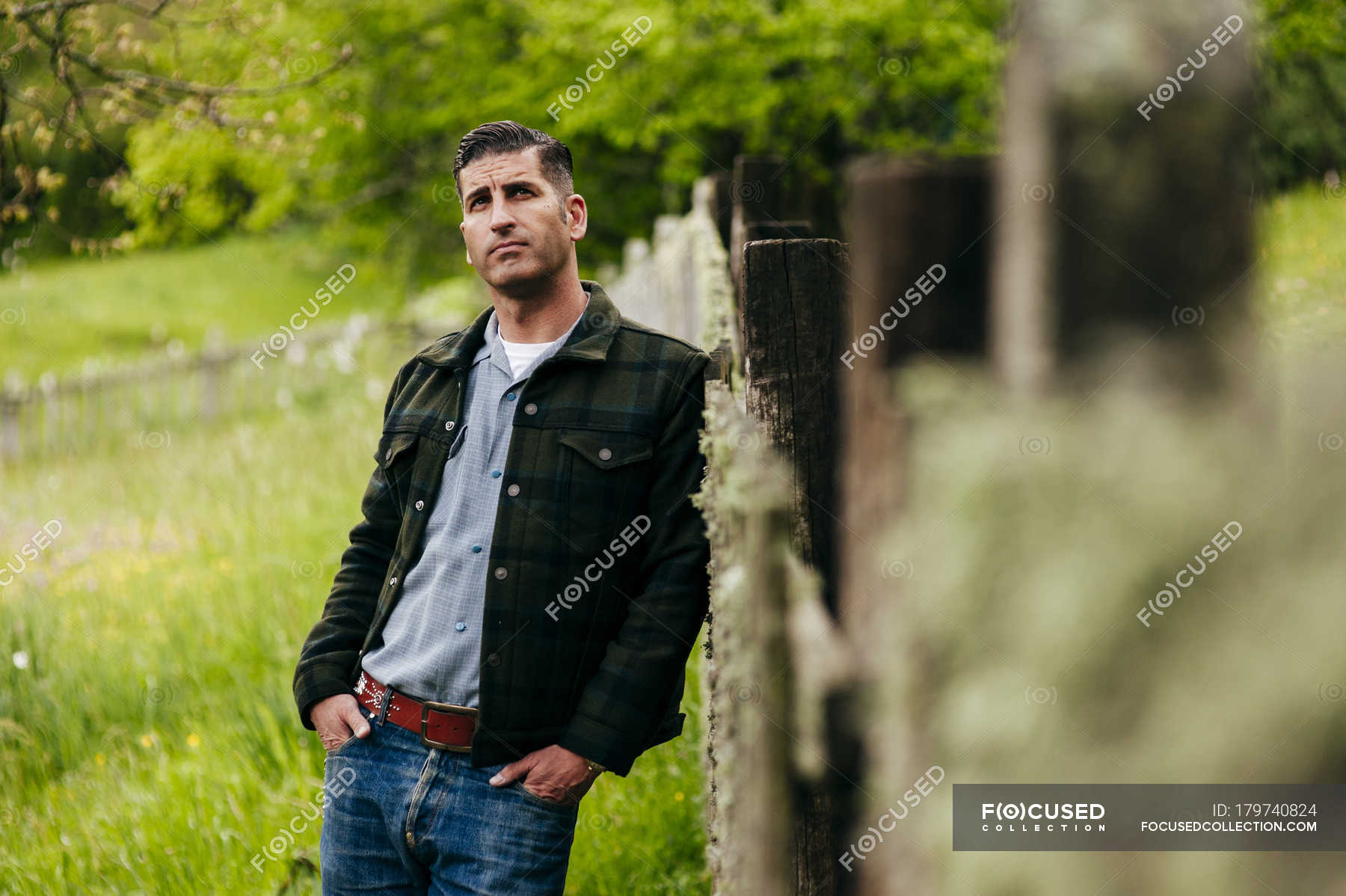 Portrait Of Thoughtful Man Leaning At Fence In Countryside And Looking
