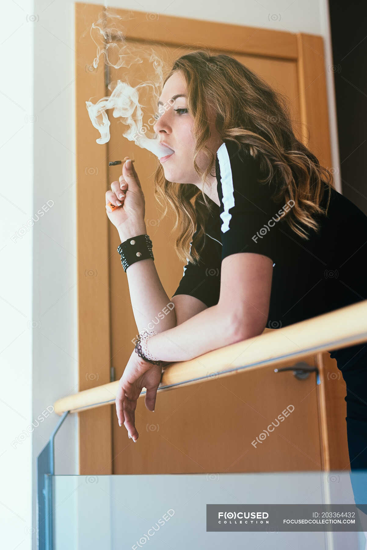 Young woman smoking a cannabis joint — flame, stoner - Stock Photo | #203364432