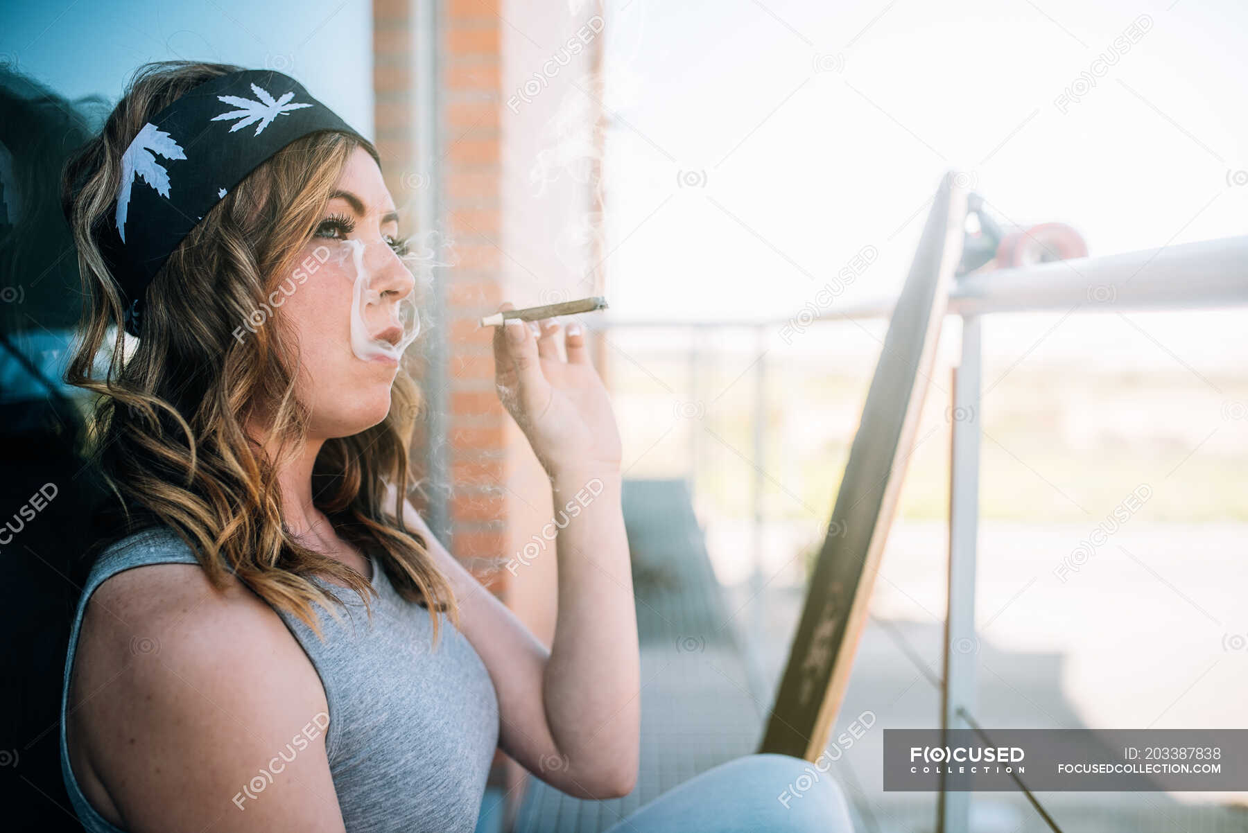 Young woman smoking a cannabis joint — puff, cap - Stock Photo | #203387838