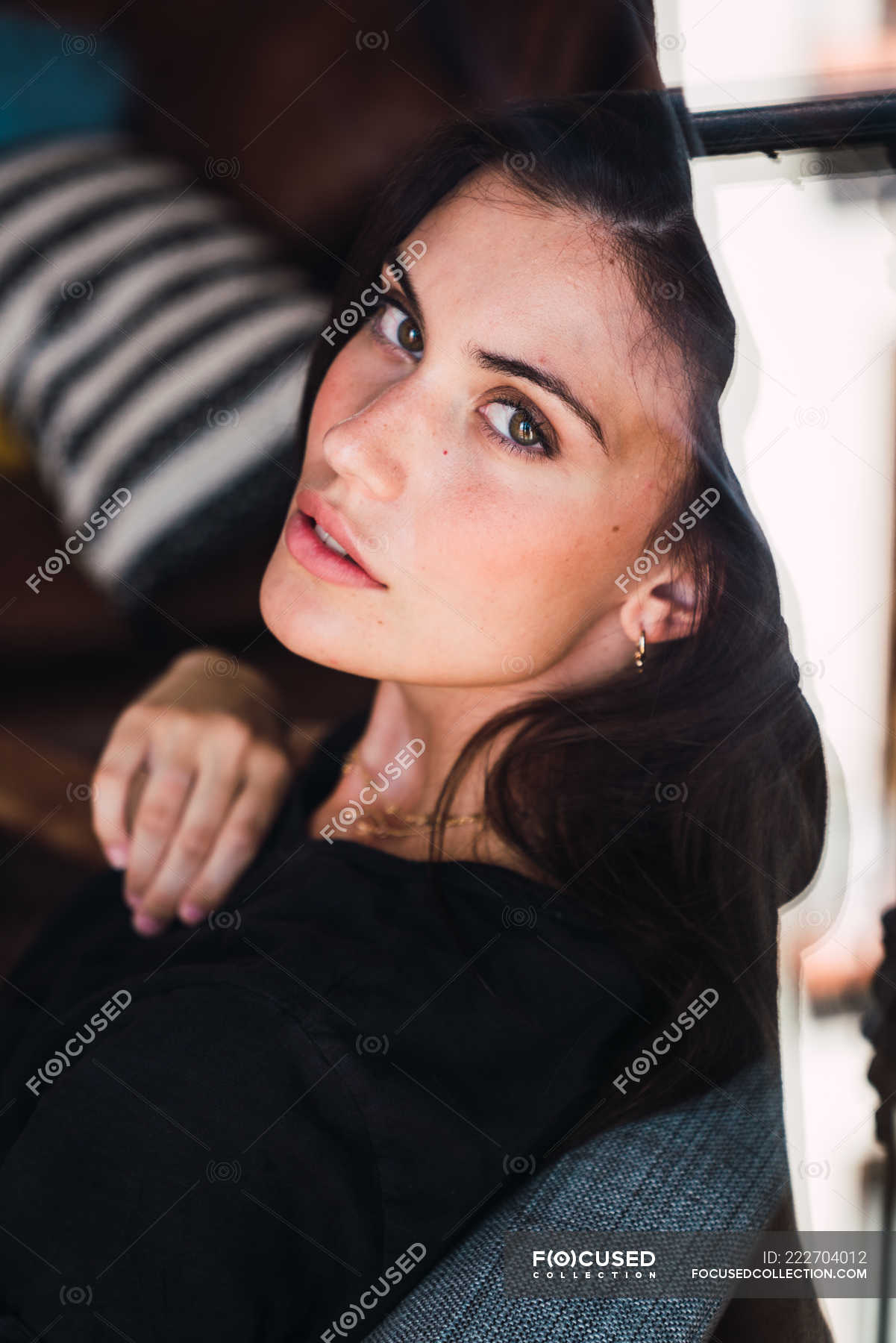 Young brunette woman sitting in armchair and looking at camera — from ...