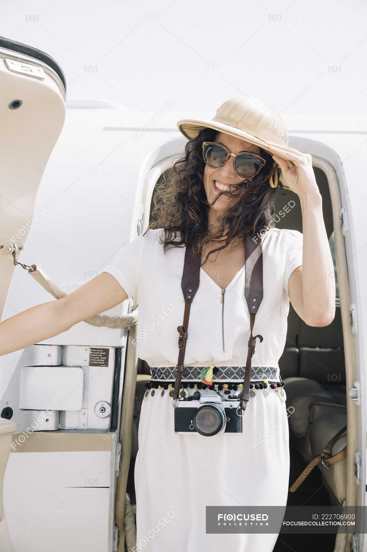 Smiling female traveler with photo camera departing from plane on ...