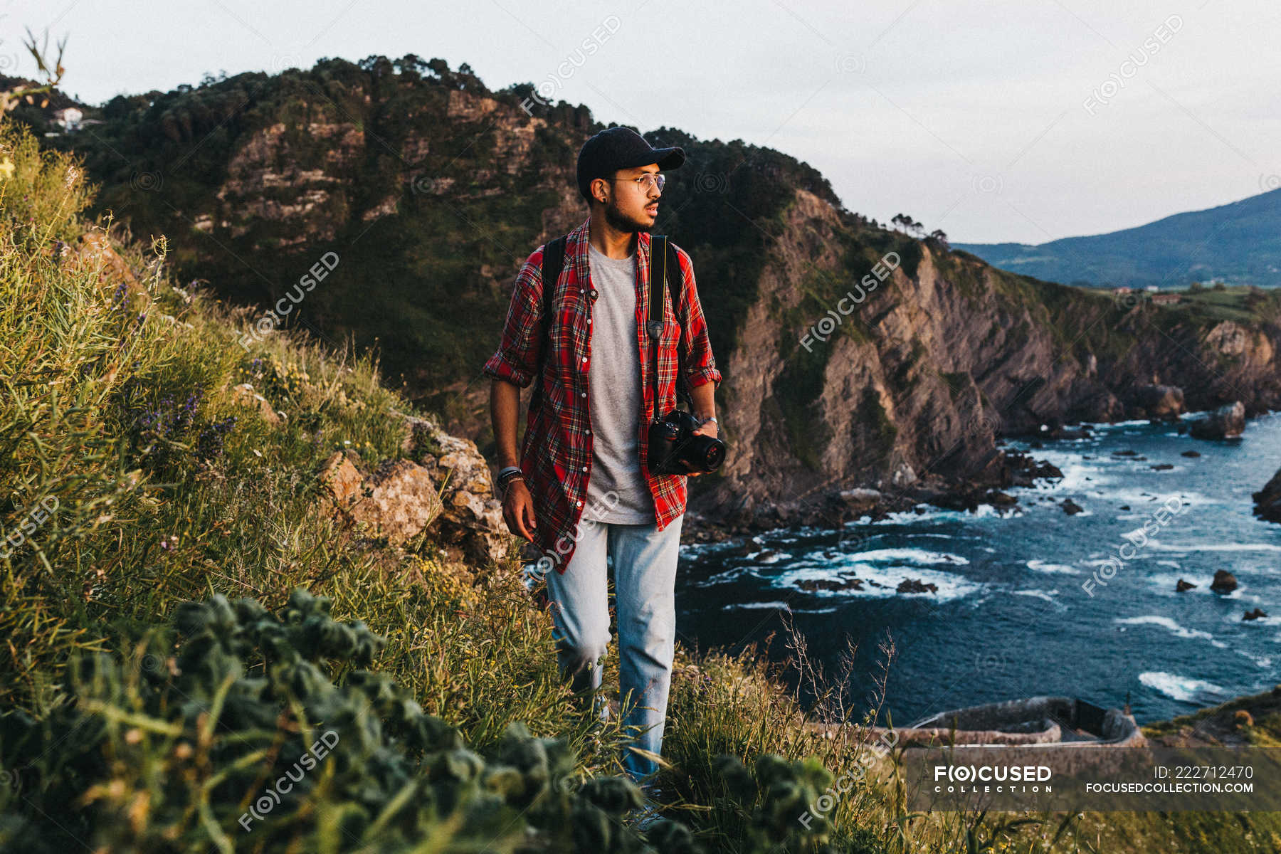 Handsome young guy with photo camera looking away while standing on ...