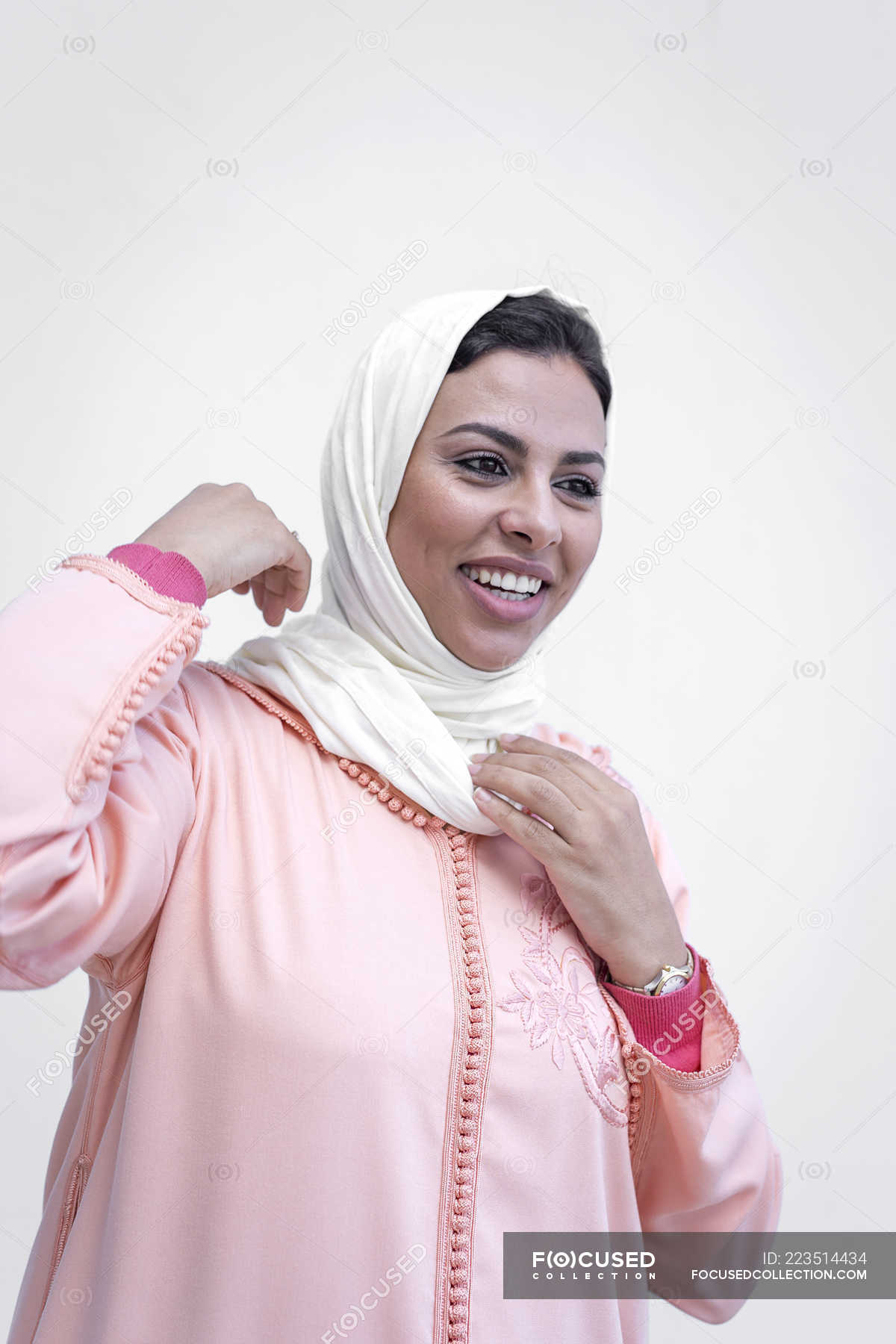 Smiling Moroccan woman in typical Arabic dress tying hijab on white ... Smiling Moroccan woman in typical Arabic dress tying hijab on white ...