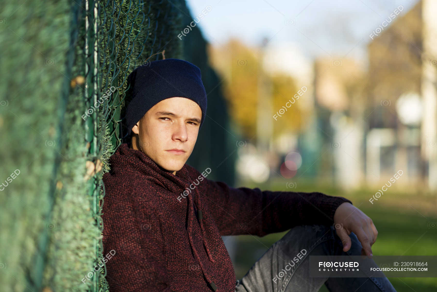 Portrait of teenage boy leaning on fence outdoors — lifestyle, teenager ...