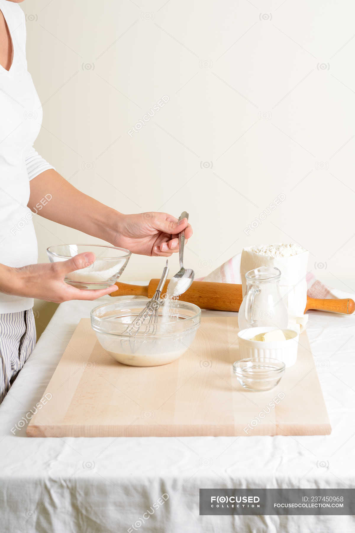 Cropped of woman pouring sugar in bowl while cooking in kitchen ... Cropped of woman pouring sugar in bowl while cooking in kitchen ...