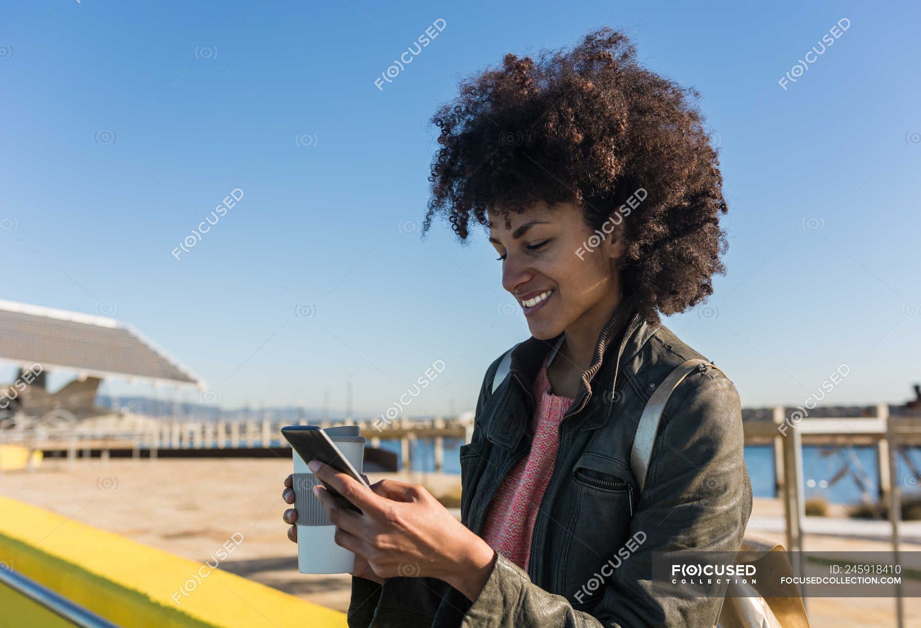 Black Woman With Afro Hair Leaning Against Brightly Colored Walls While