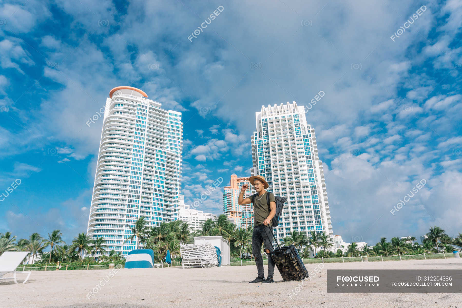 Attractive young man on sunny summer holiday, building on background ...