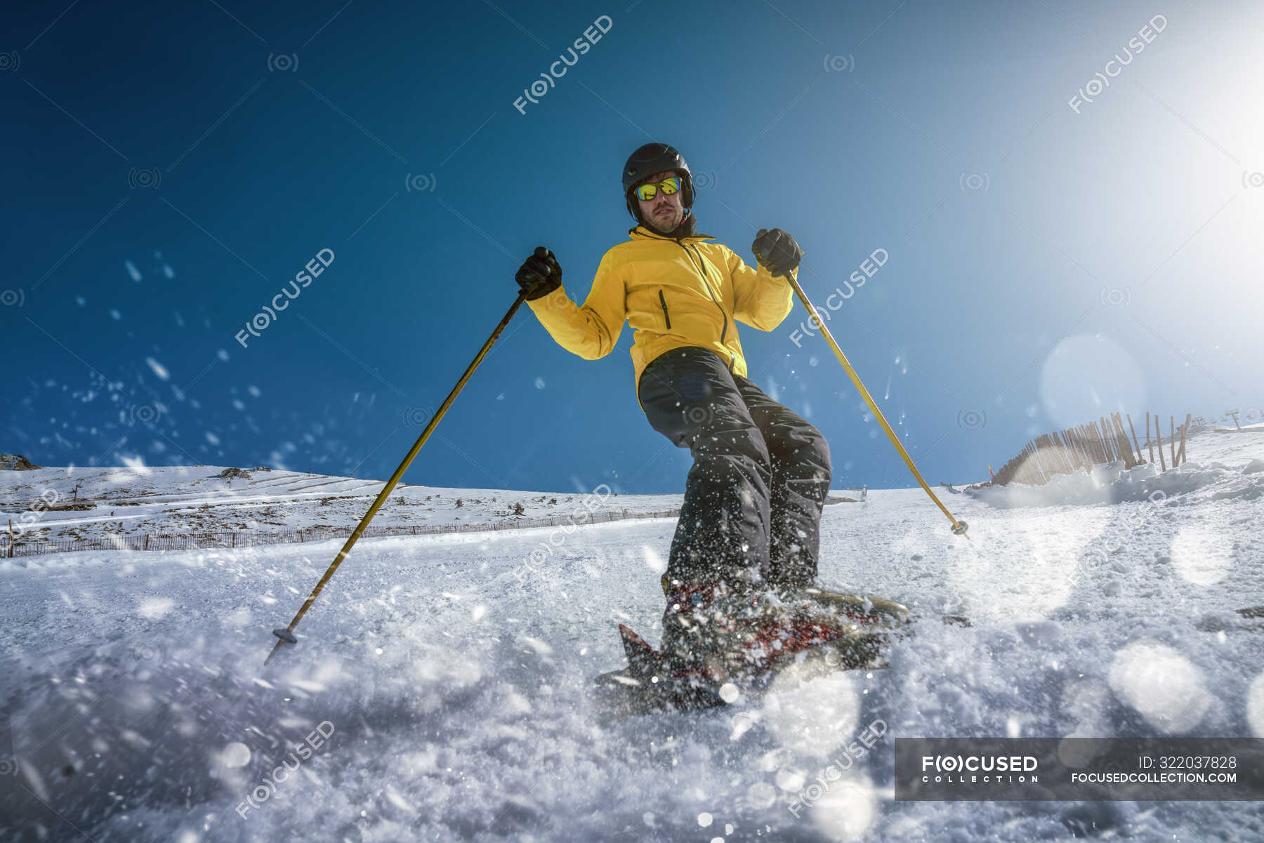 Full body young man in yellow outwear and sunglasses riding skis on ...