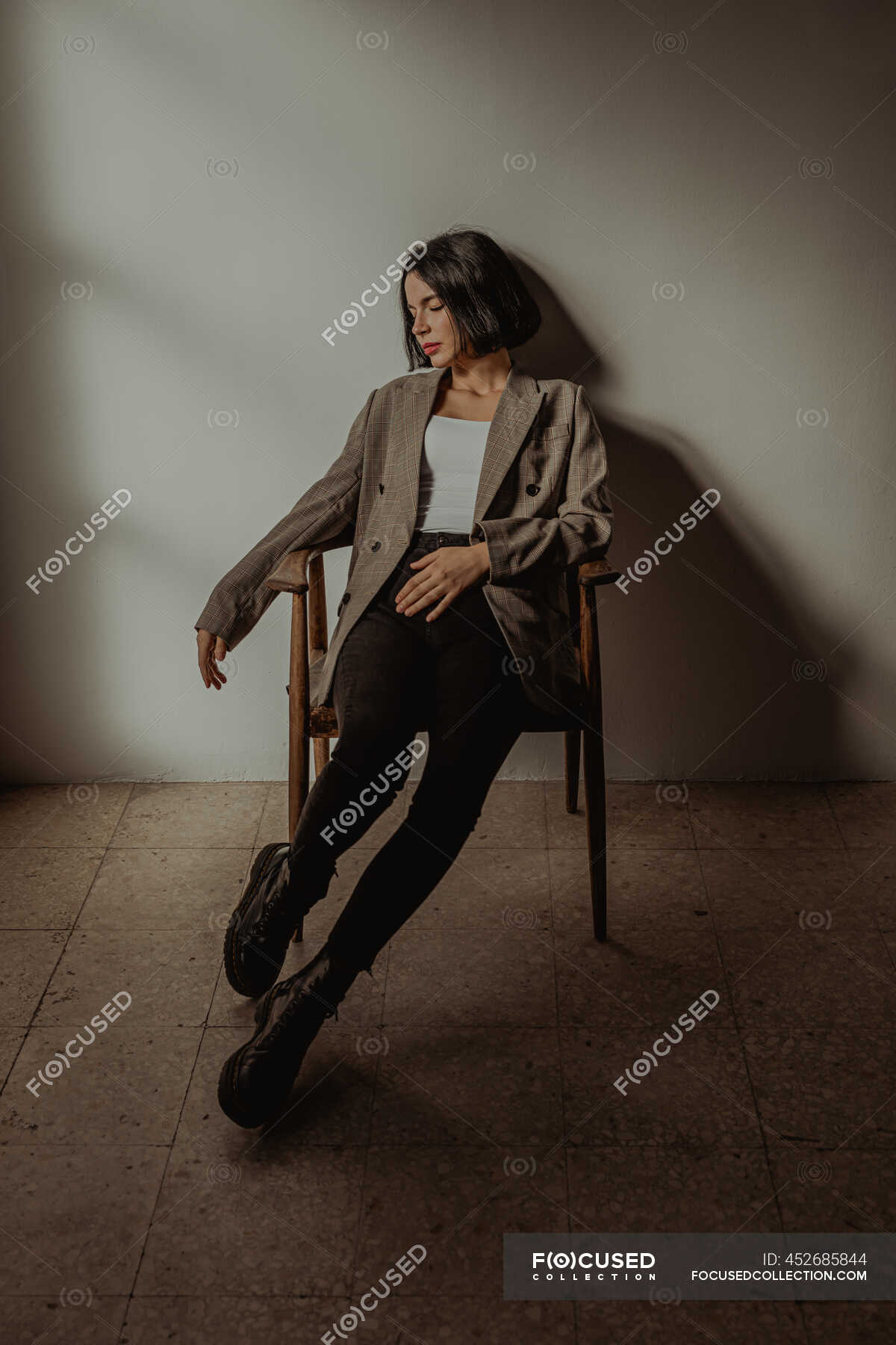 Relaxed female wearing trendy clothes sitting on chair while touching ...