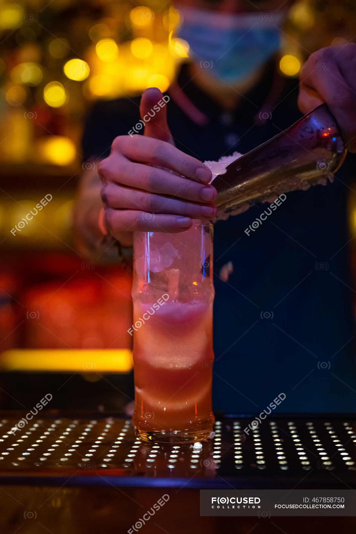 Hands of unrecognizable bartender putting crushed ice into the cup while preparing a cocktail in ...