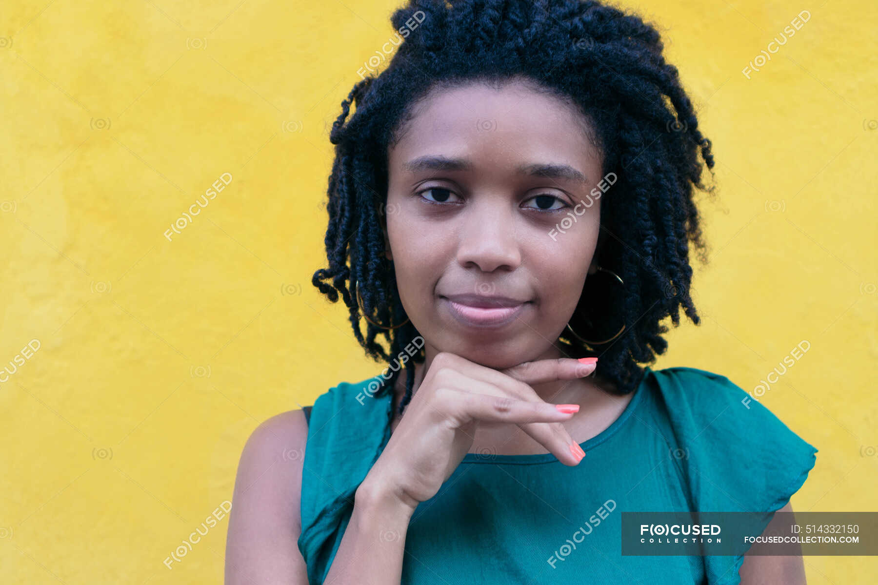 Portrait of young African woman with afro hairstyle leaning on a wall ...