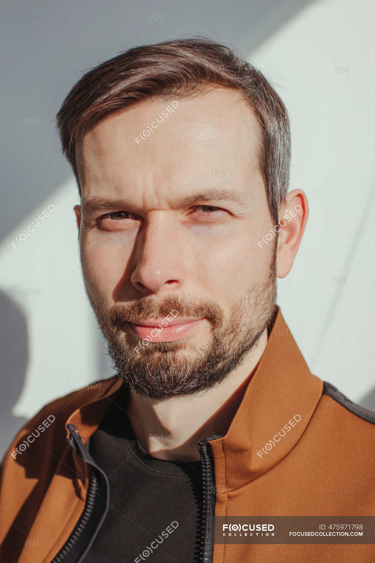 Portrait of a handsome man with a beard standing in sunlight — indoors ...